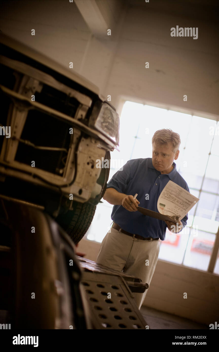 A man is inspecting a car in a garage Stock Photo - Alamy