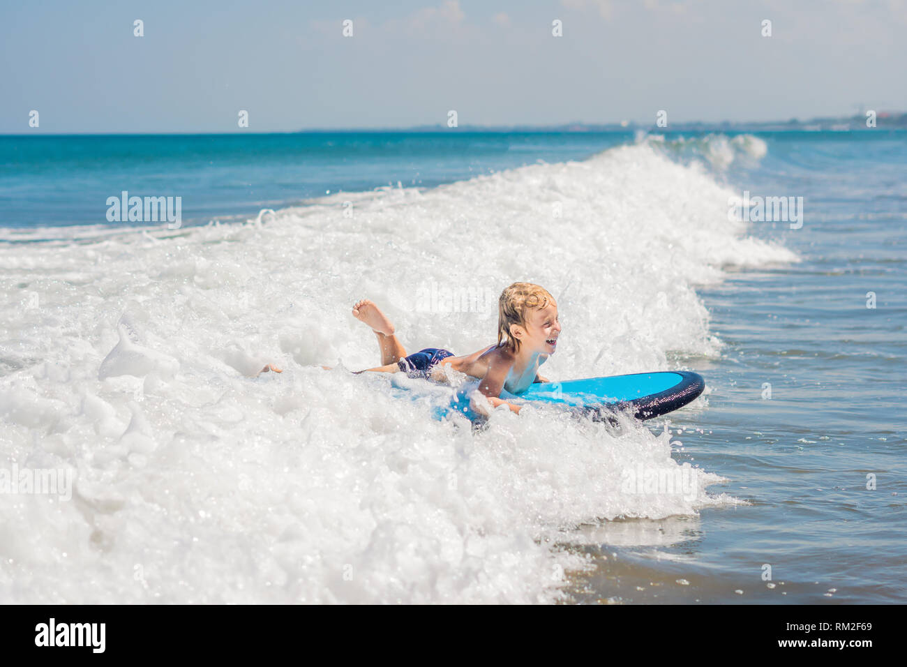 Happy baby boy - young surfer ride on surfboard with fun on sea waves ...