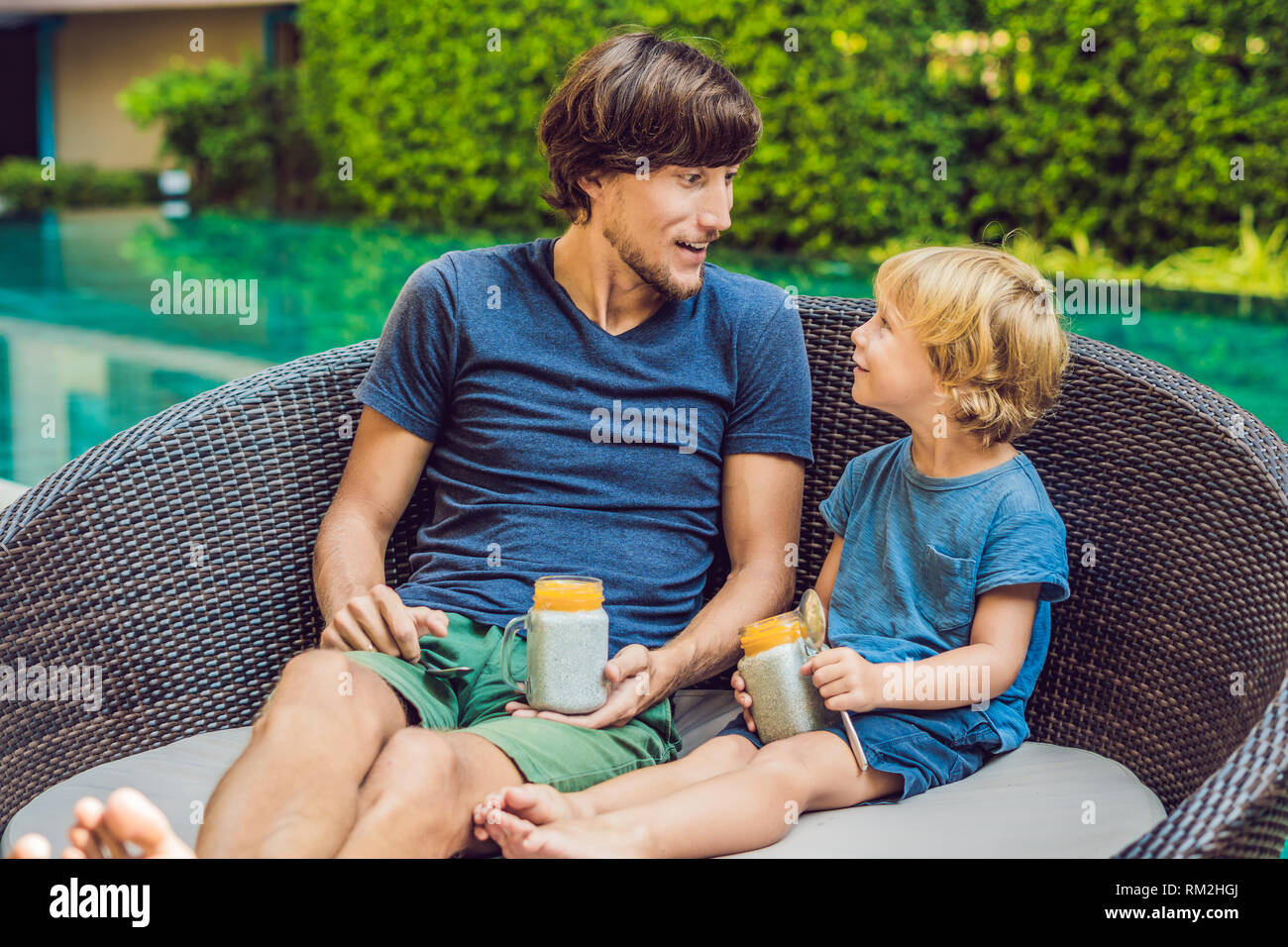 Father and son eat dessert with chia seeds and mangoes by the pool in ...