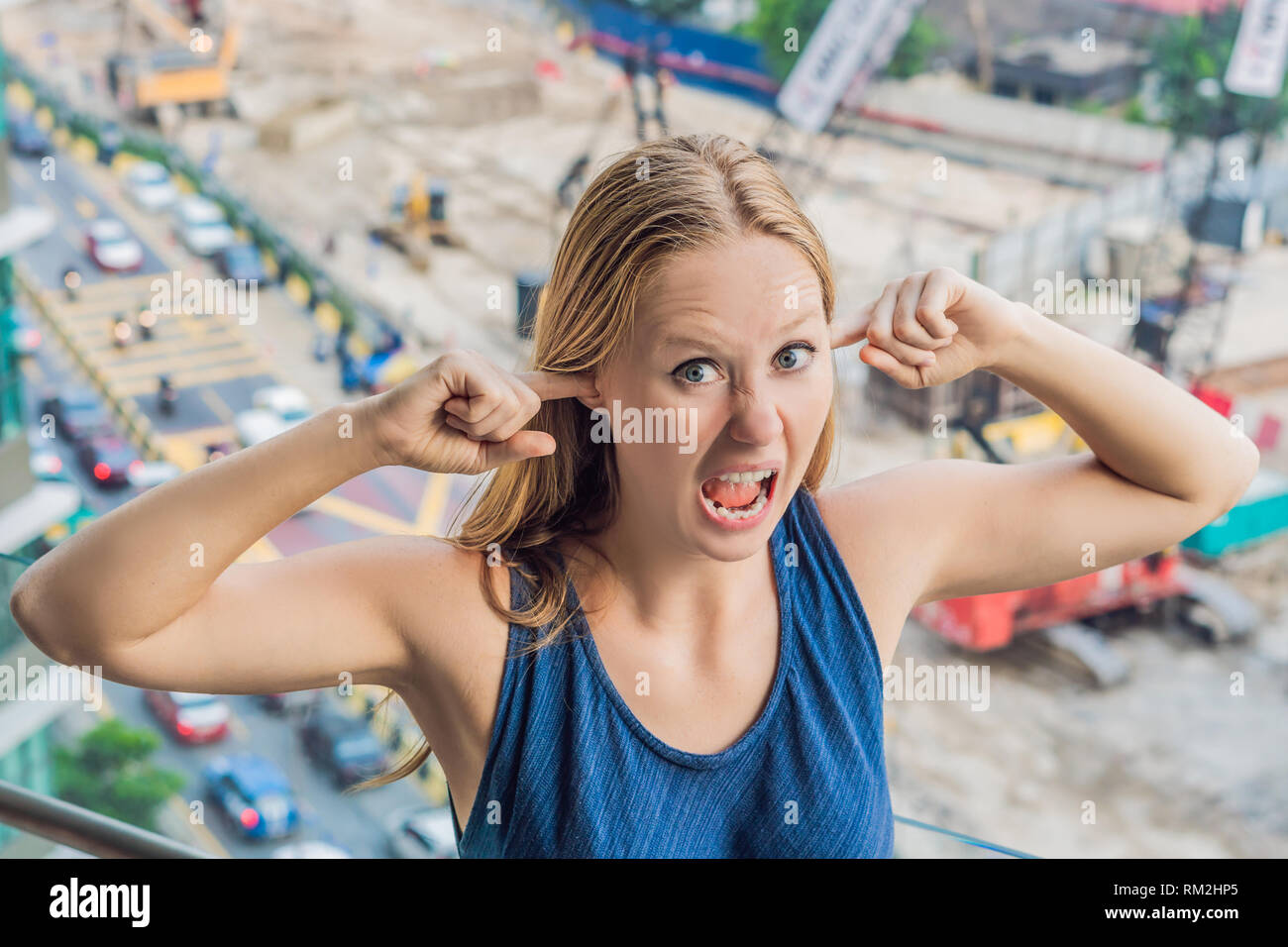 A young woman by the window annoyed by the building works outside ...