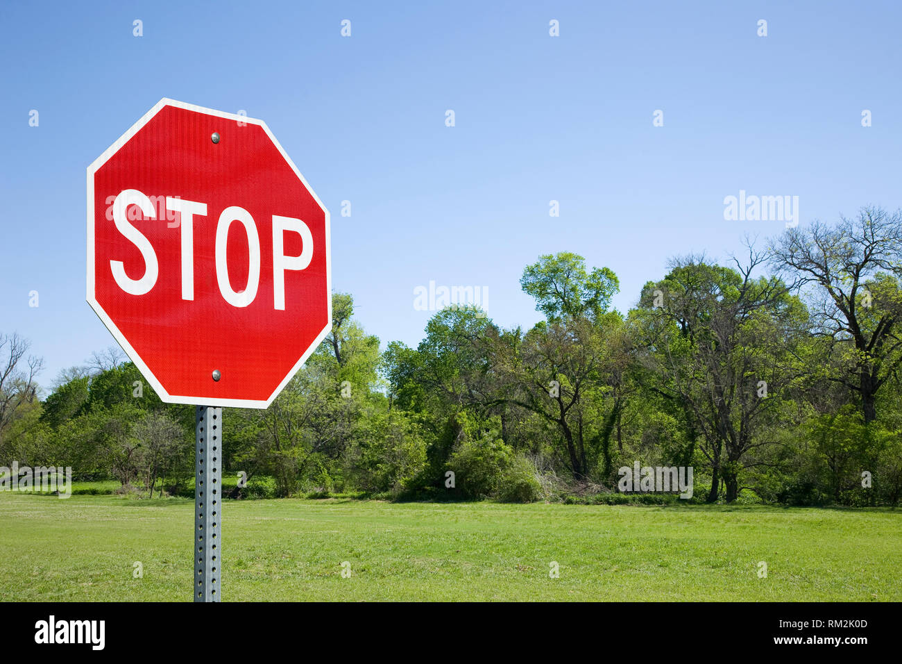 Stop Sign With Green Trees And Field Stock Photo - Alamy