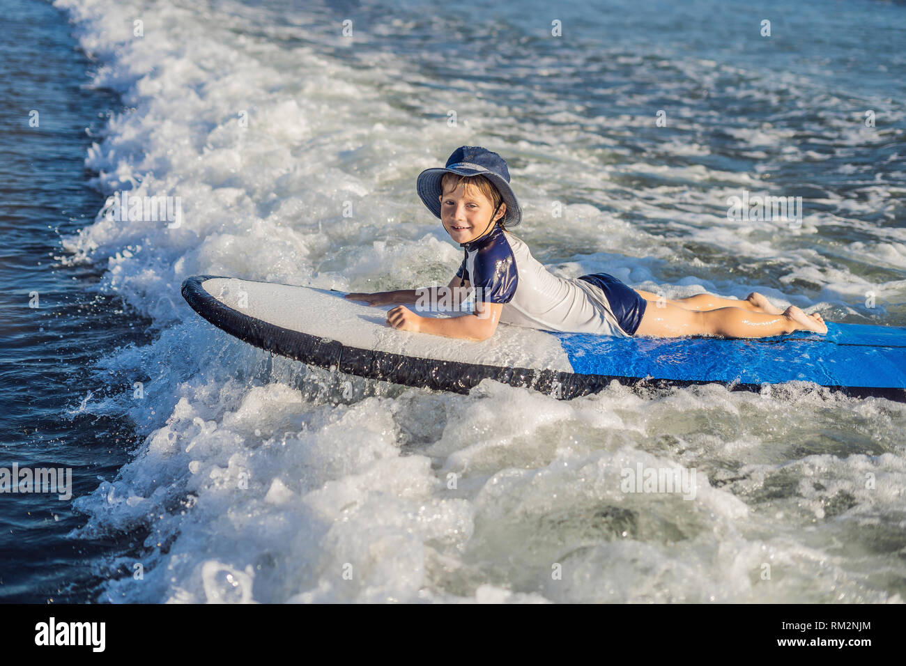 Happy baby boy - young surfer ride on surfboard with fun on sea waves ...