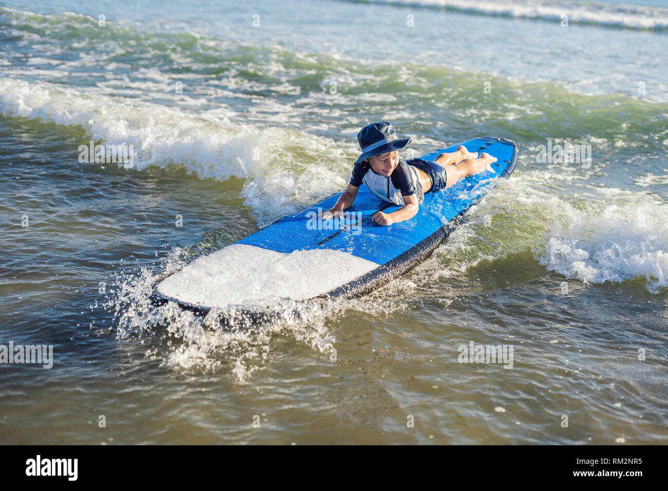 Happy baby boy - young surfer ride on surfboard with fun on sea waves ...