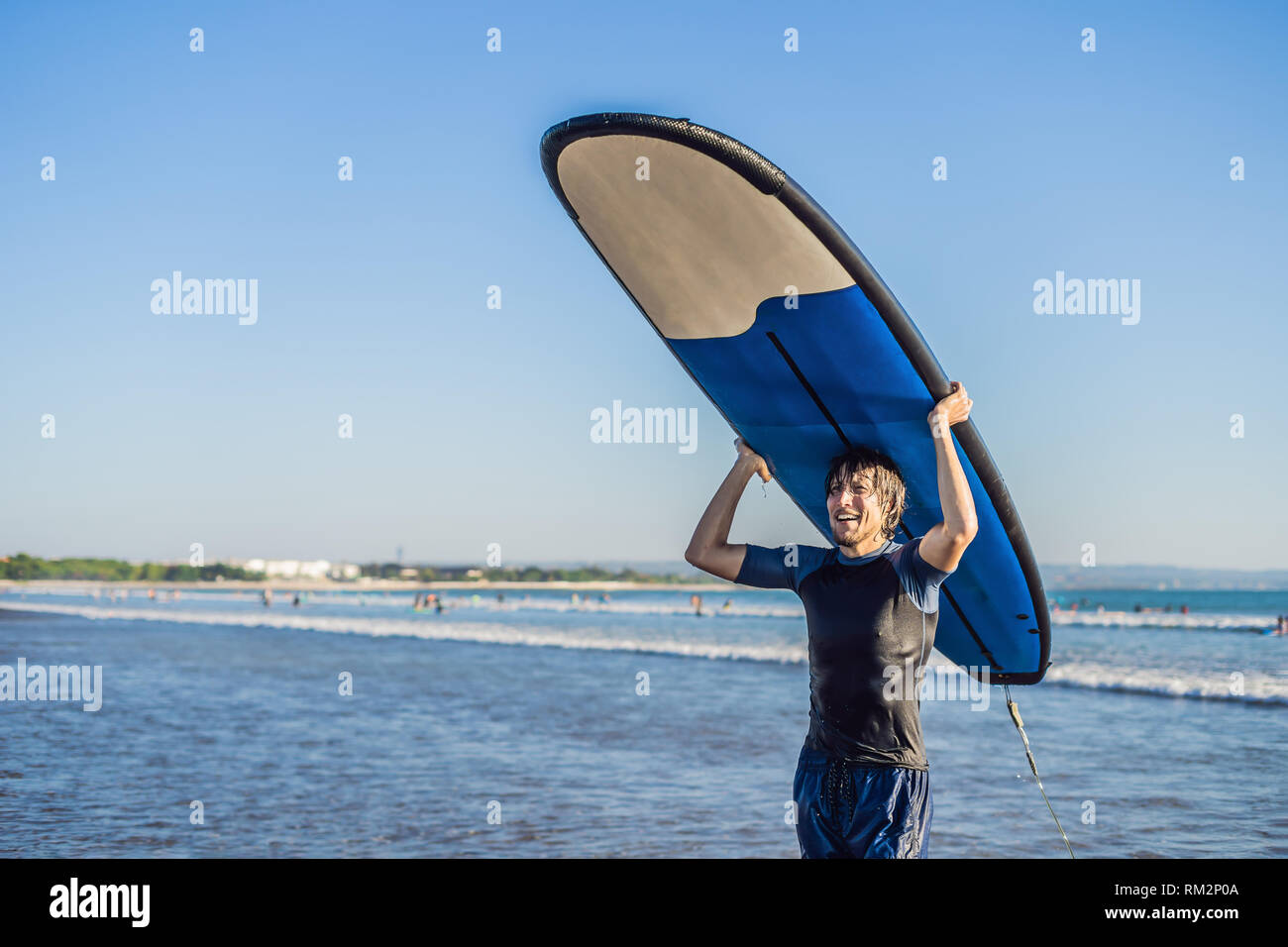 Man carrying surfboard over his head. Close up of handsome guy with ...