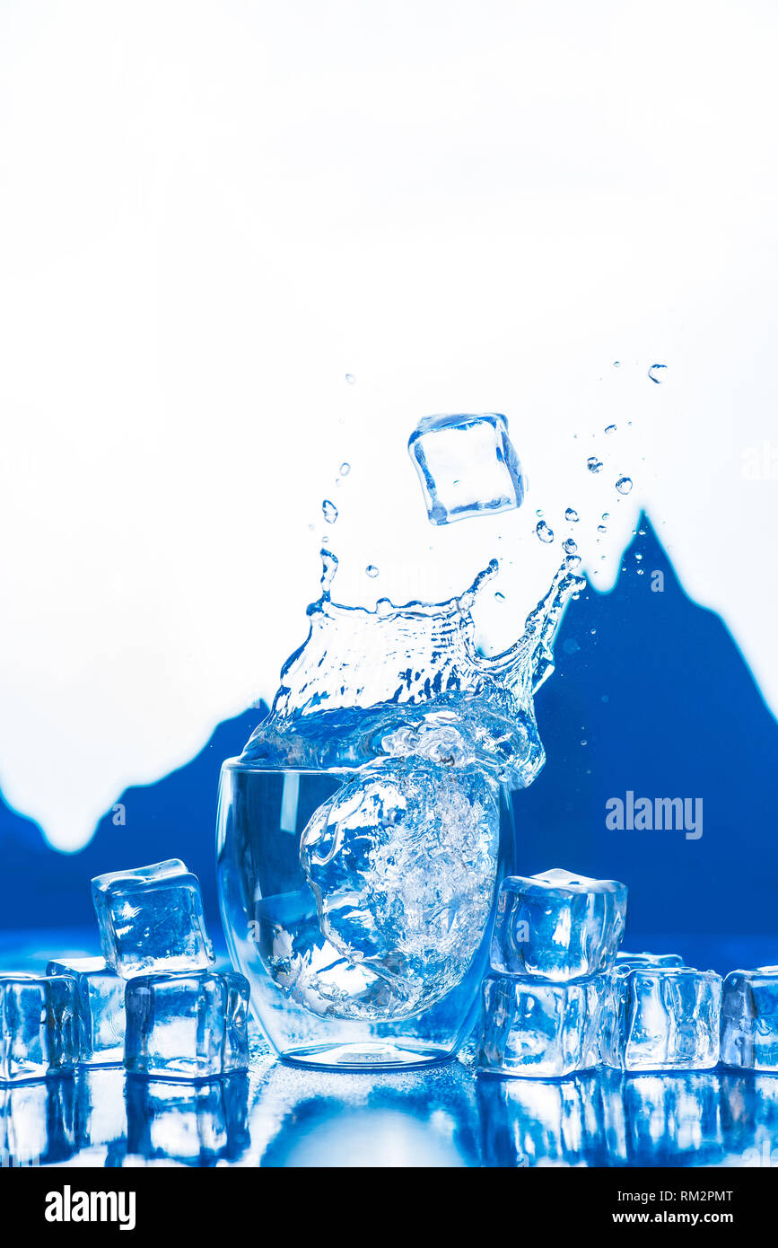 Crystal clear water splash in a double wall glass with mountain peaks ...