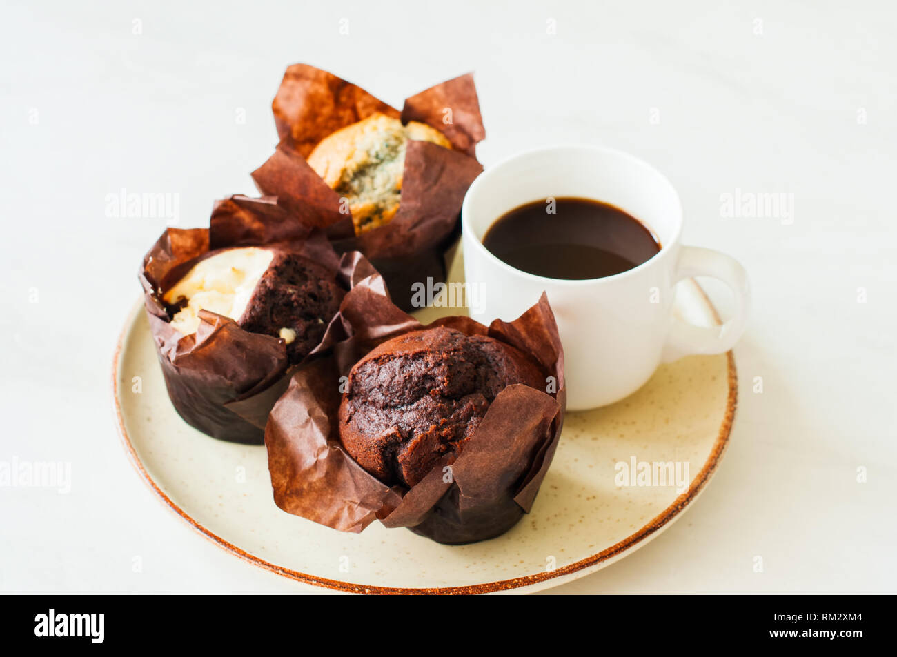 Three type of muffins and a cup of coffy on a plate. White background ...