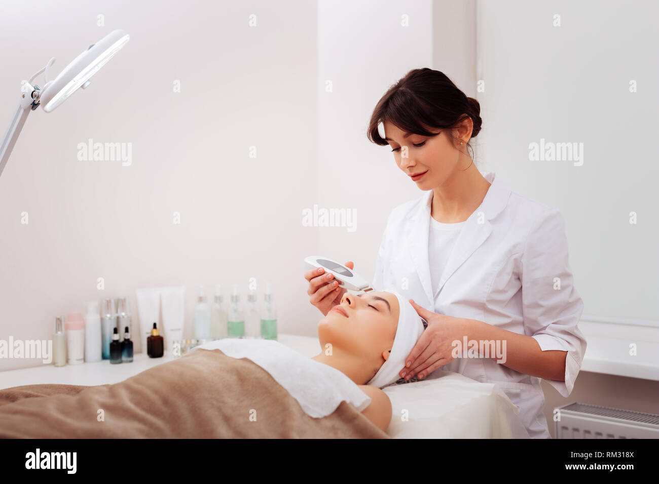 Professional positive beautician performing a beauty procedure Stock ...
