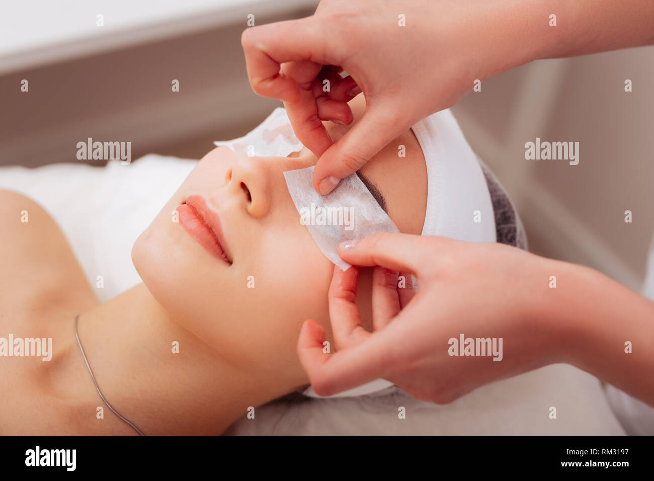 Nice professional female cosmetologist applying eye patches Stock Photo ...