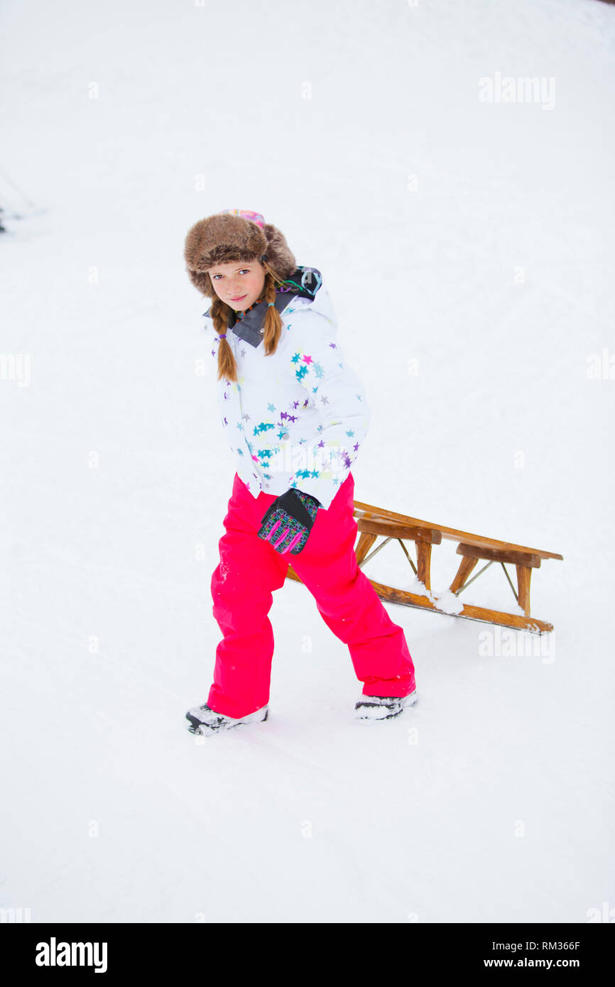 Girl in winter pulling her sled through the snow Stock Photo - Alamy