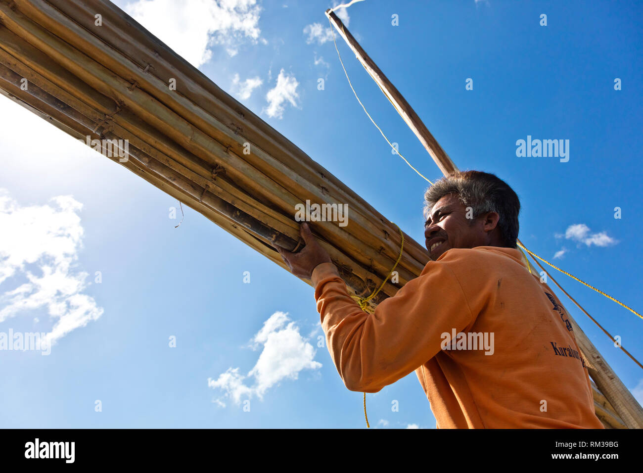 A MOKEN MAN stows his sail on his traditional boat to KHO RA ISLAND in ...