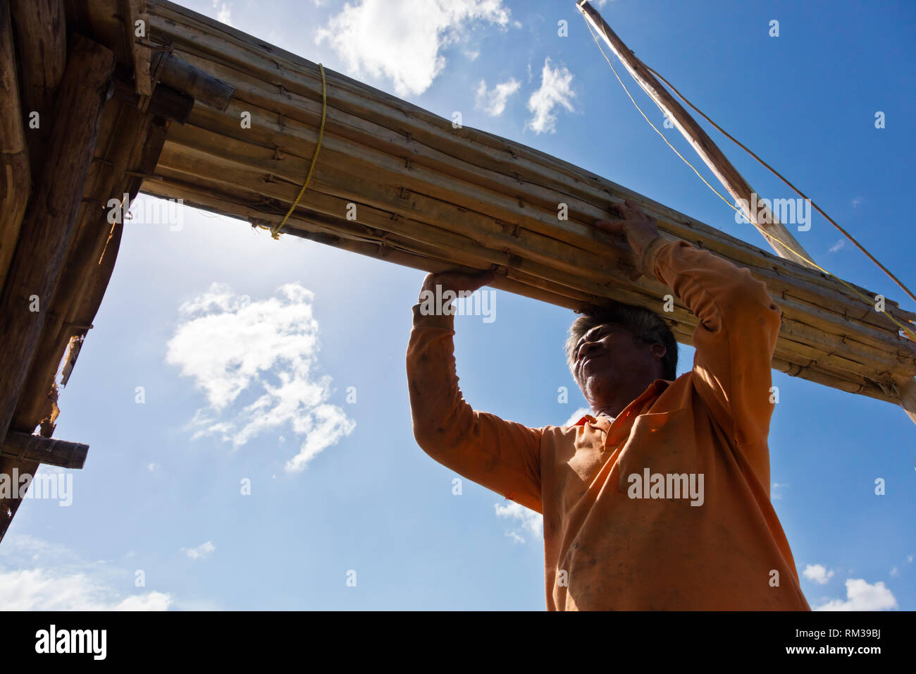 A MOKEN MAN stows his sail on his traditional boat to KHO RA ISLAND in ...