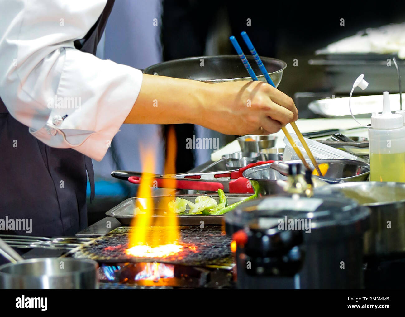 Chef cooking with flame in a frying pan on a kitchen stove, Chef in ...