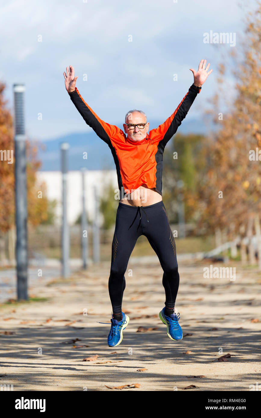 Senior runner man jumping arms up after running Stock Photo - Alamy