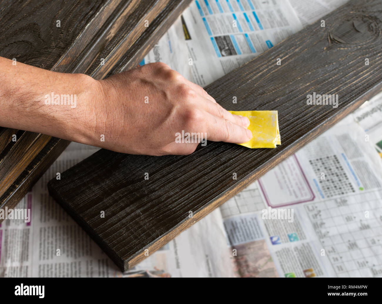 Man's hand with sandpaper polishes painted board, manual wood treatment ...