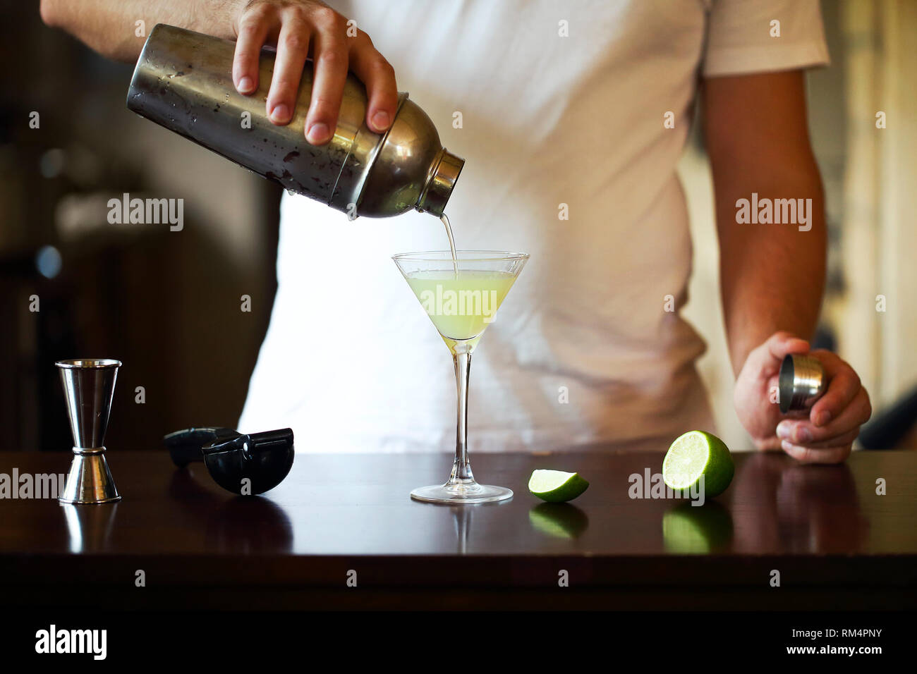 Barman at work, preparing cocktails. Pouring martini to cocktail glass ...