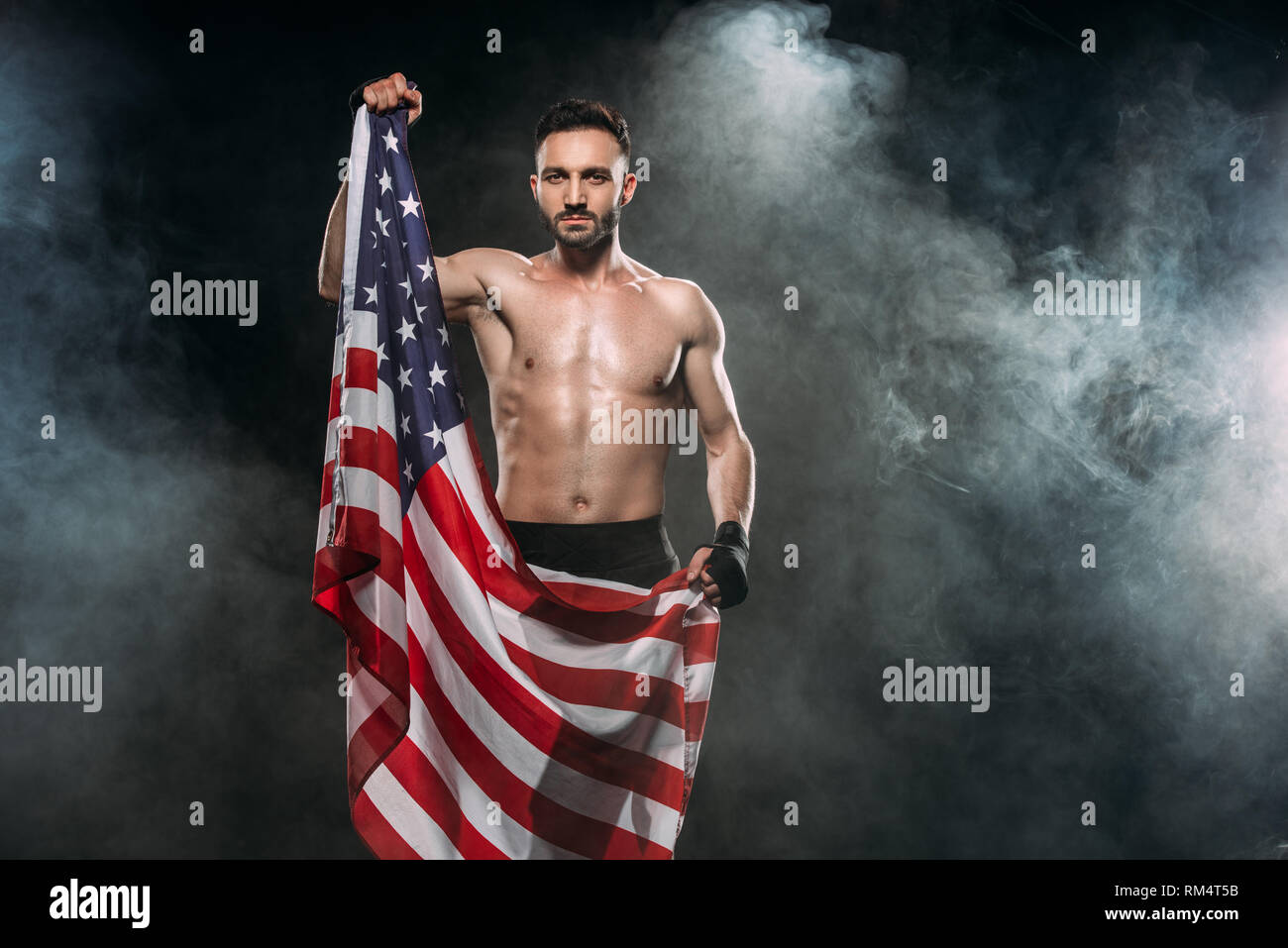 muscular man holding american flag on black with smoke Stock Photo - Alamy