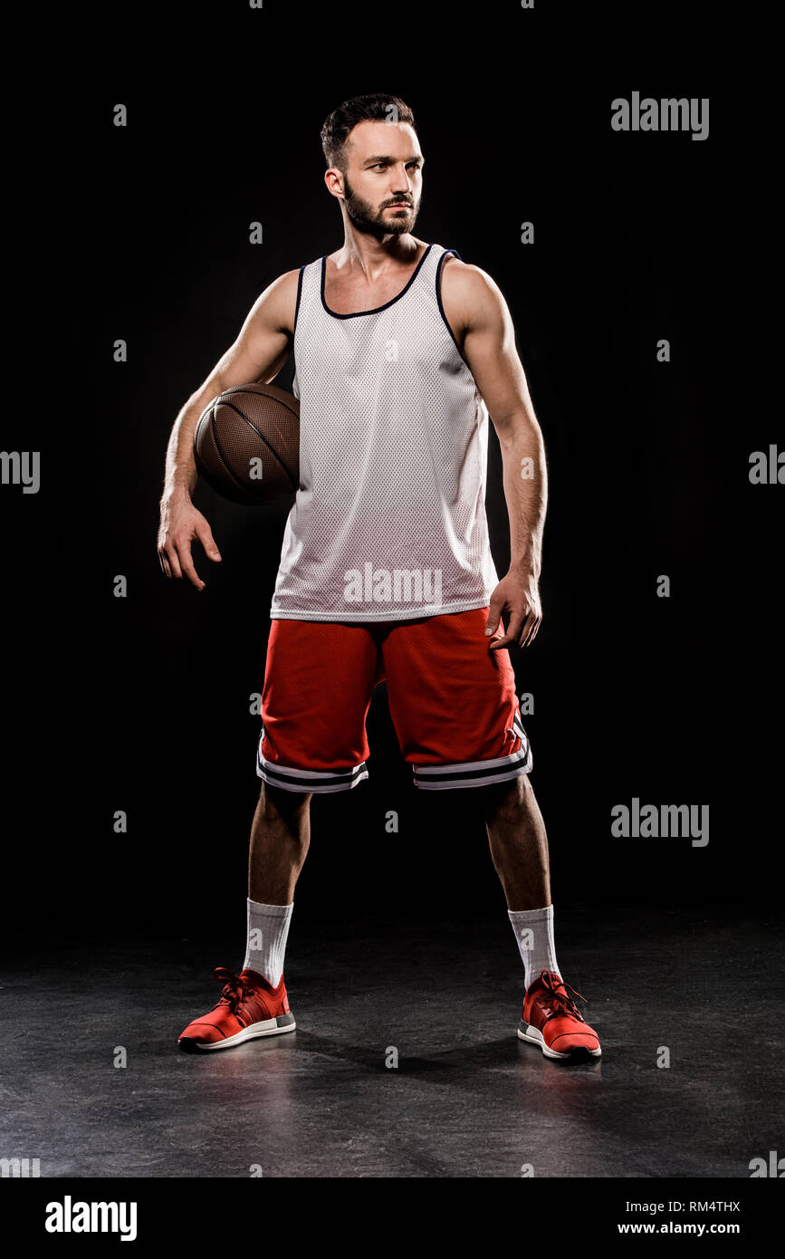 muscular basketball player standing with ball on black background Stock ...