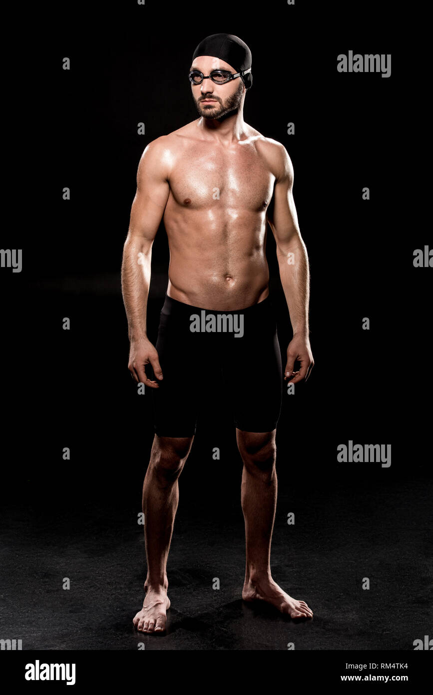 confident swimmer standing in swimming cap and goggles on black ...