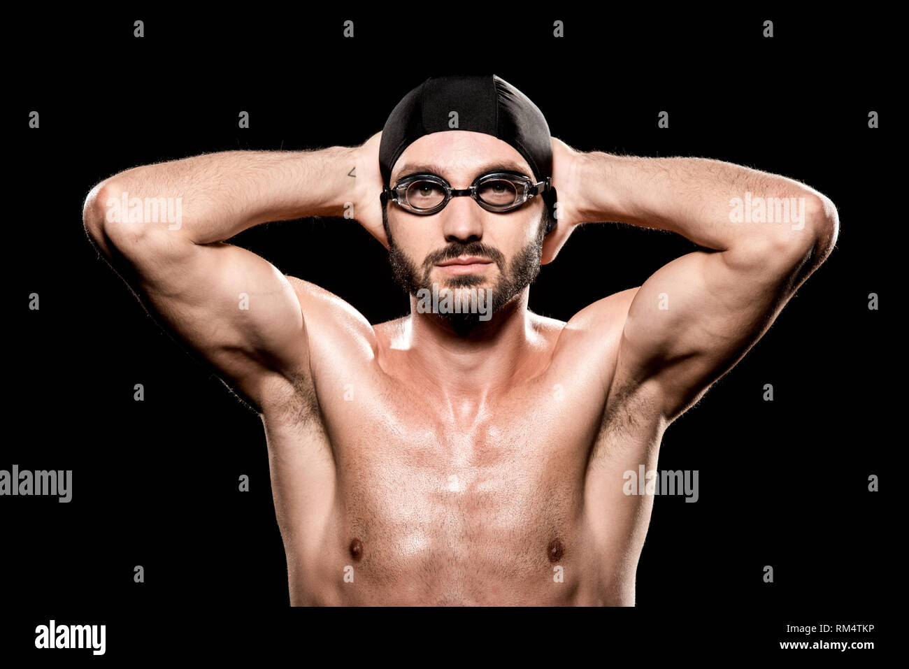 handsome swimmer posing in swimming cap and goggles isolated on black ...