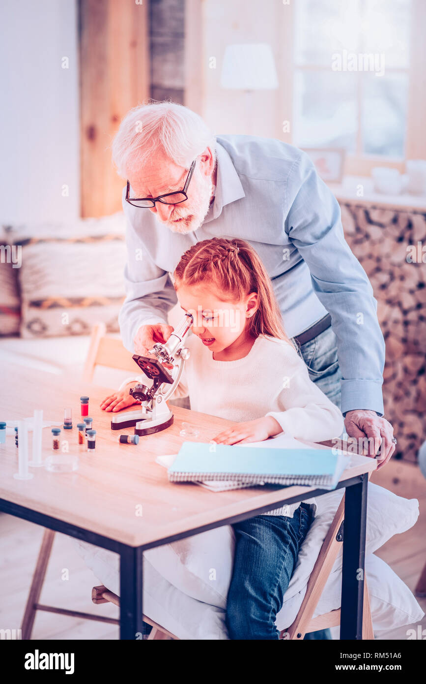 Old man helping kid watching in microscope Stock Photo - Alamy