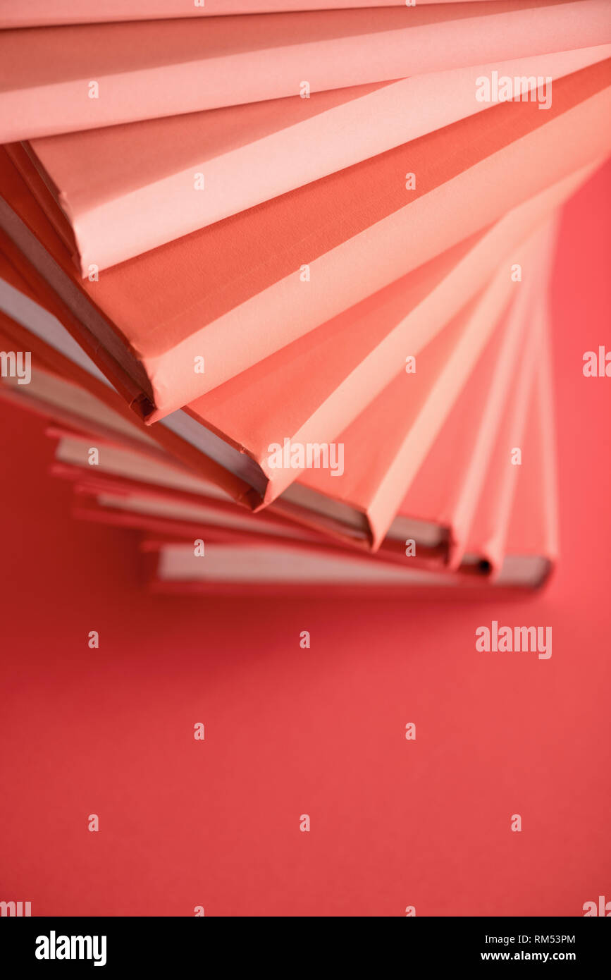 stack of books on living coral background with copy space. Pantone ...
