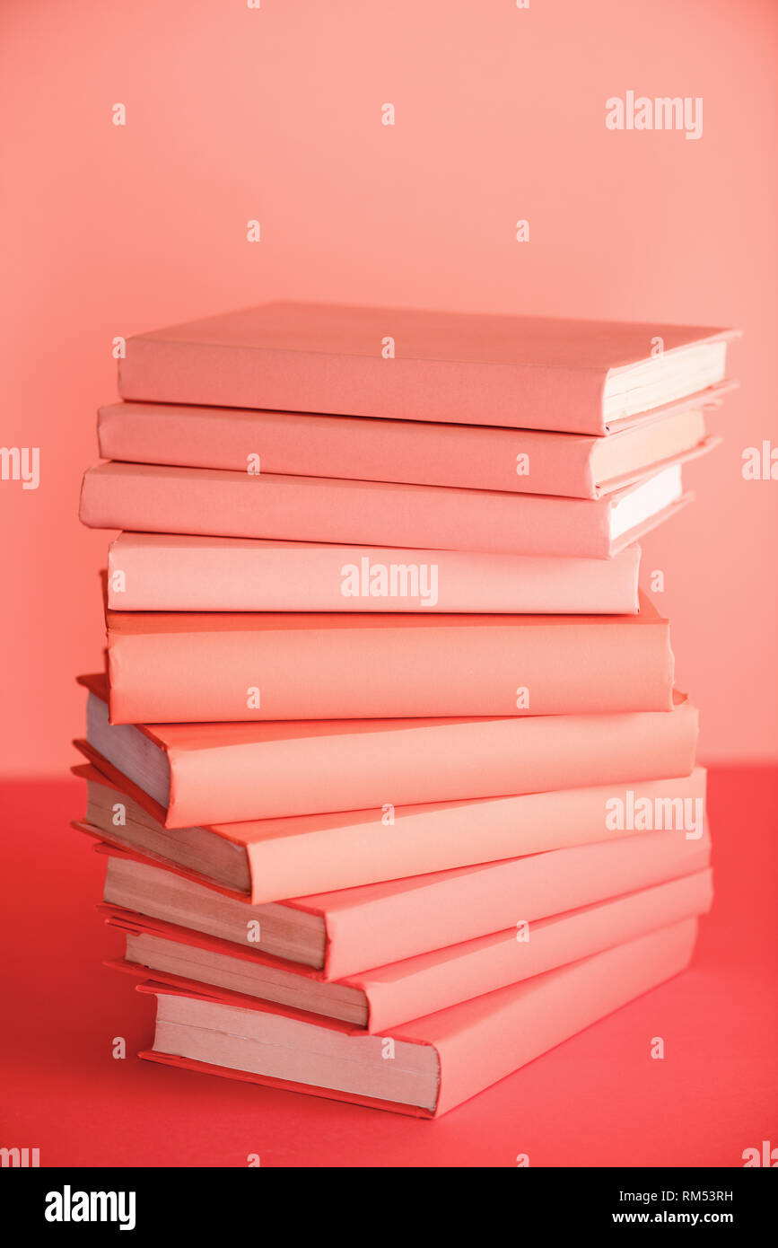 stack of books on living coral background. Pantone color of the year ...