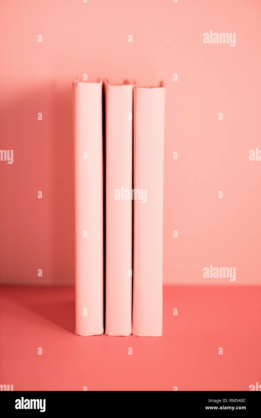 three books on living coral background. Pantone color of the year 2019 ...