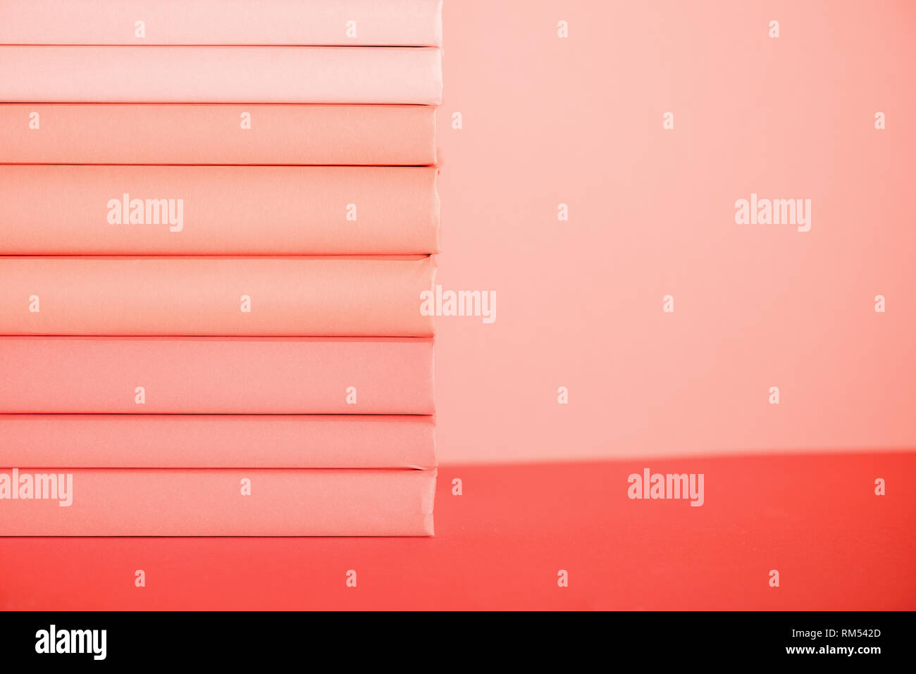 stack of books on living coral background. Pantone color of the year ...