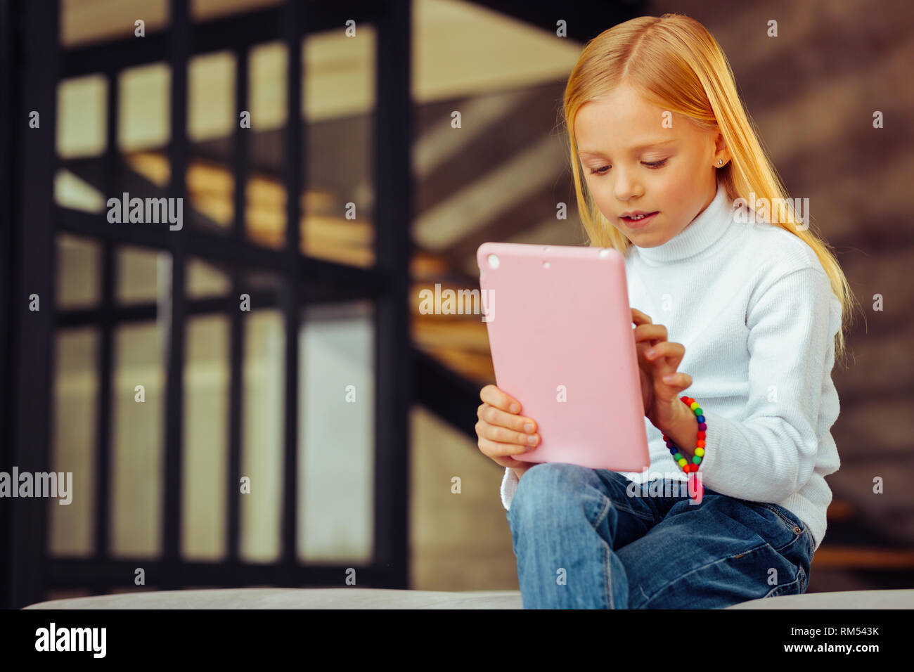 Concentrated longhaired preschooler staring at her tablet Stock Photo ...
