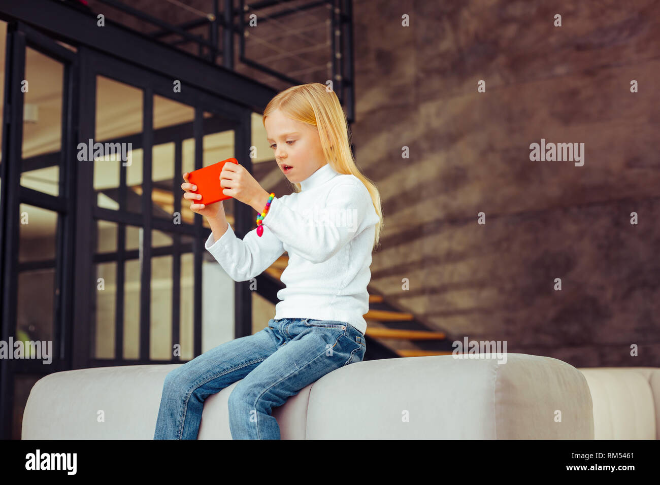 Serious kid staring at screen of her gadget Stock Photo - Alamy