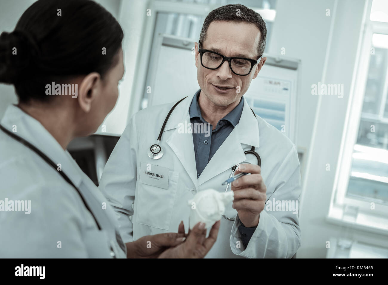 Male doctor in clear glasses pointing on the heart model Stock Photo ...
