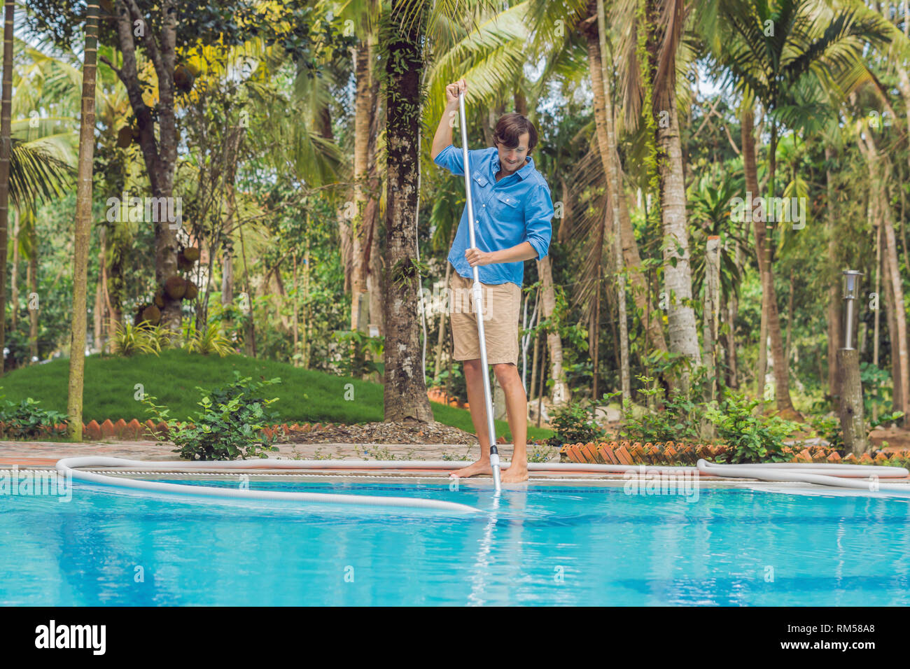 Cleaner of the swimming pool . Man in a blue shirt with cleaning ...
