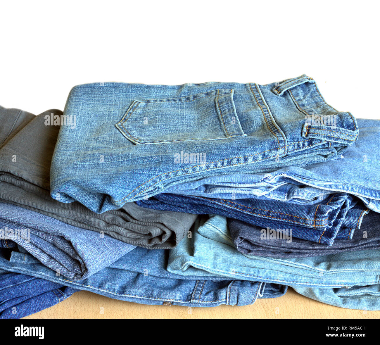 Many fashionable youth jeans lie in a mess isolated on white background ...