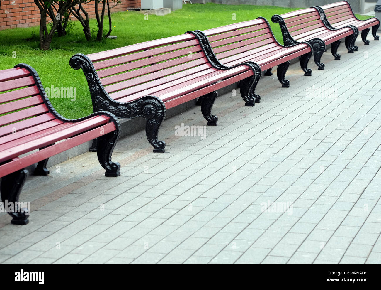 Row of empty brown wooden benches in city park in spring diagonal view ...