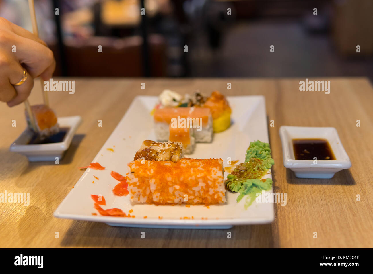 Friends eating sushi and dip in sauce in sushi bar Stock Photo - Alamy