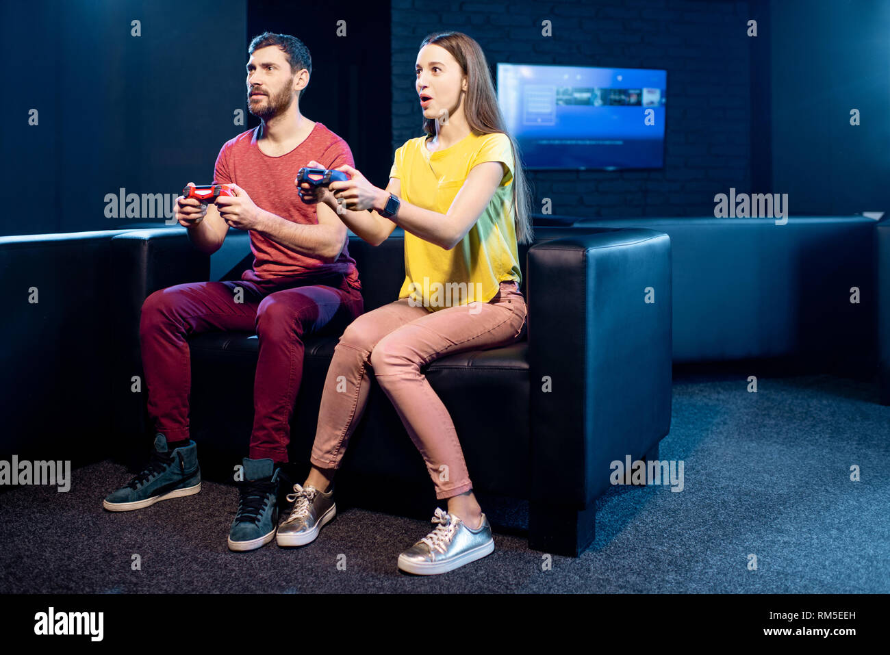 Young couple playing video games with gaming console sitting on the ...