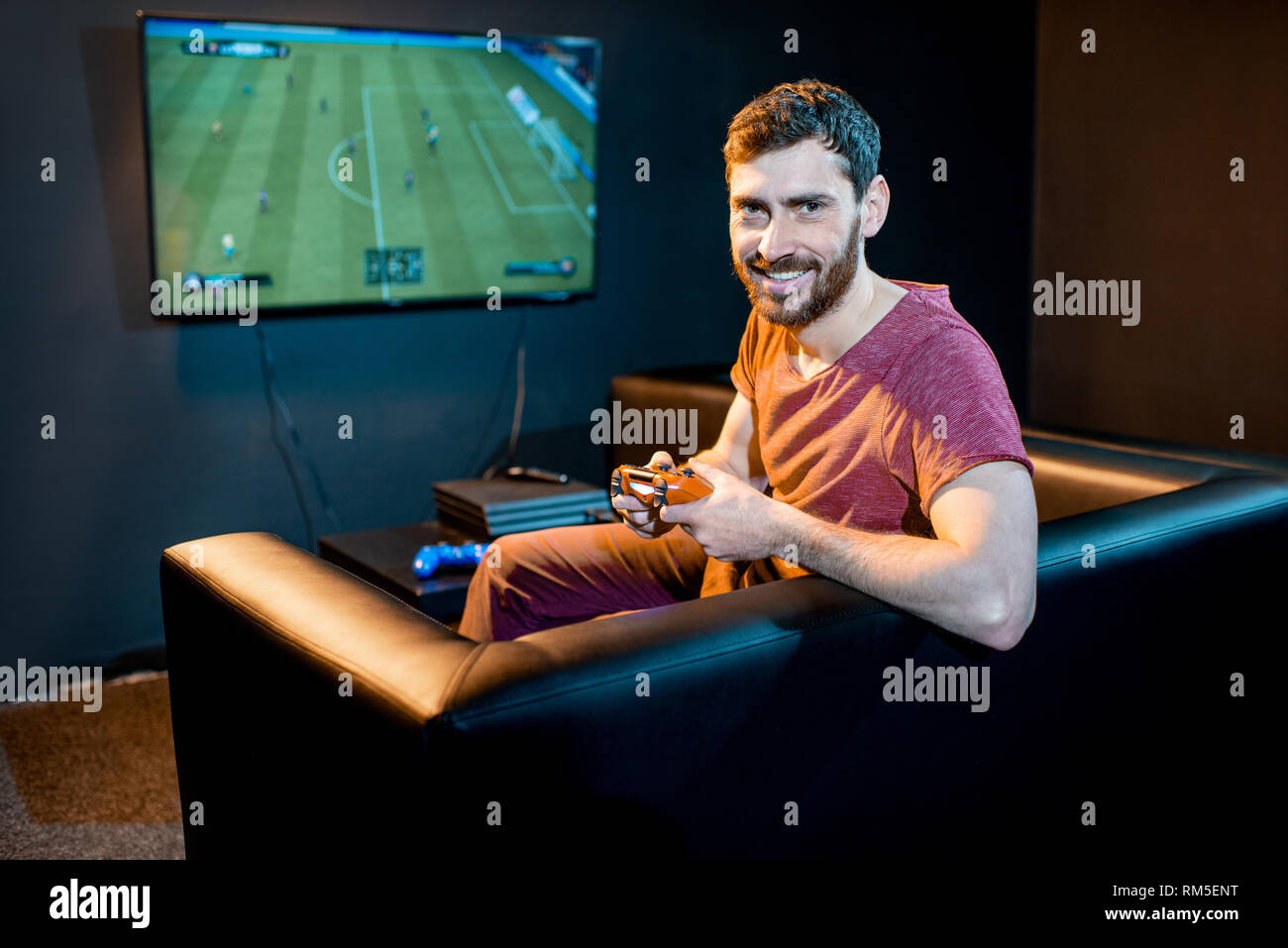 Portrait of a happy man with joy stick playing football game with ...