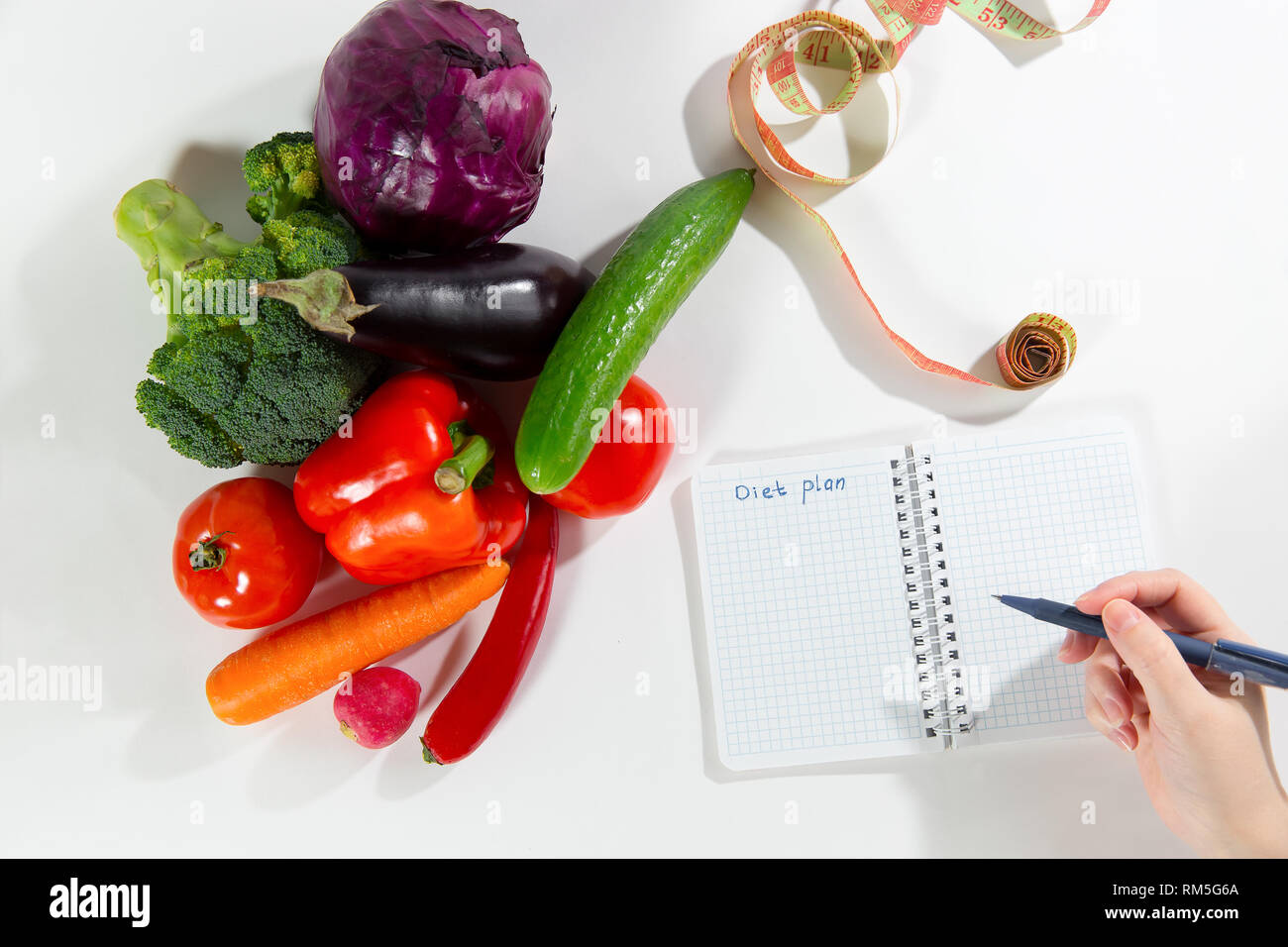 Female nutritionist hand writing diet plan in notebook against fresh ...