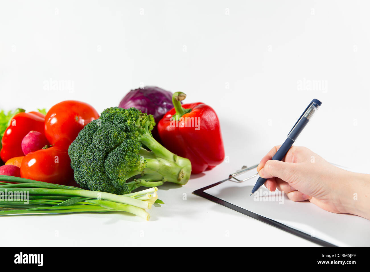 Female nutritionist doctor writing vegetable diet plan. Organic ...