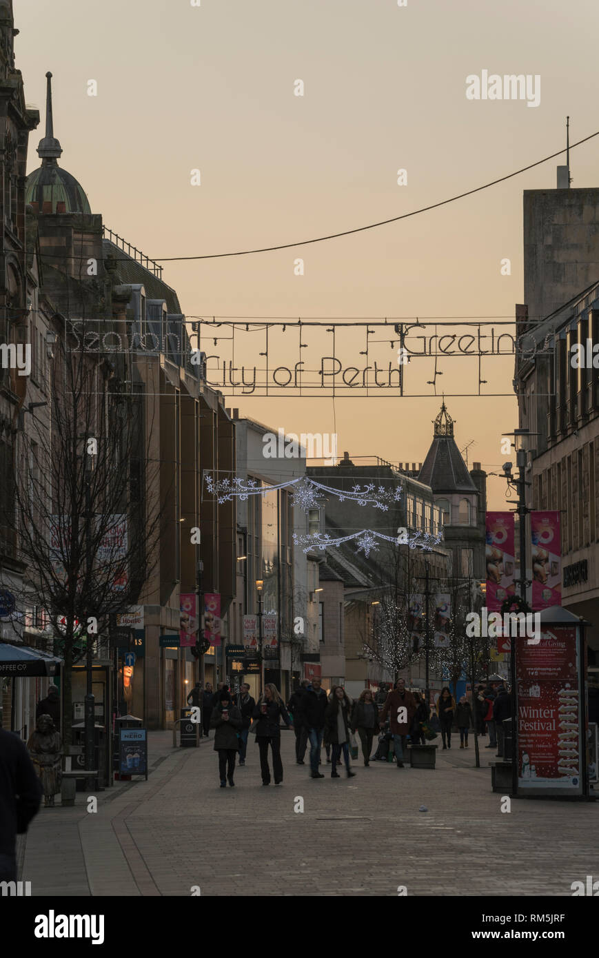 High street shoppers under Christmas lights at dusk in Perth, Scotland ...