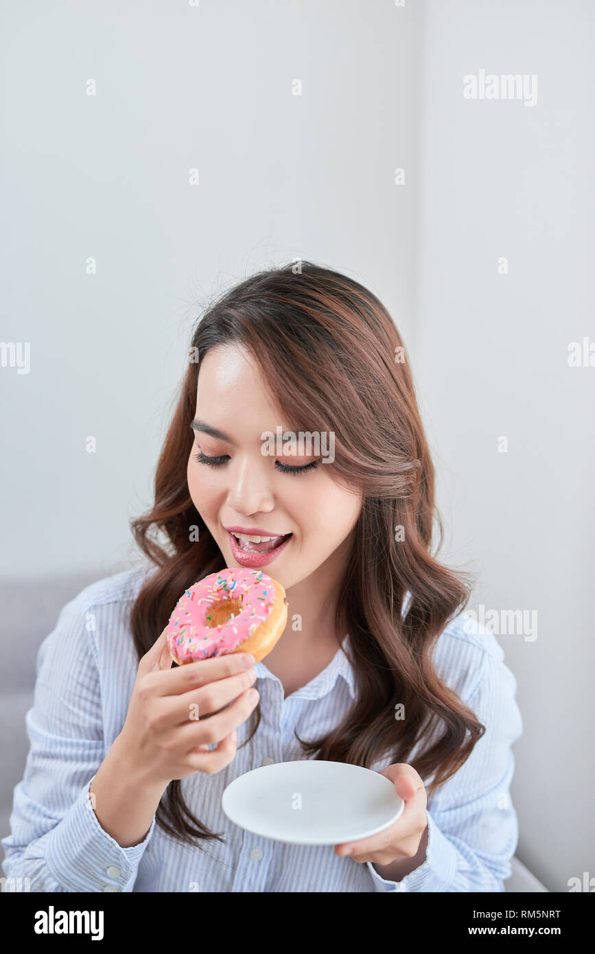 Portrait of beautiful young woman eating donuts at home Stock Photo - Alamy