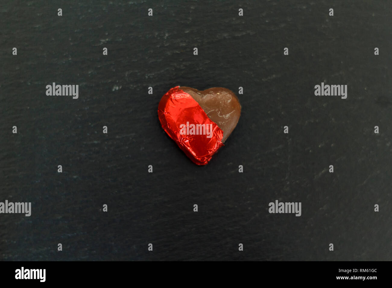 One Chocolate Heart with wrapping half open on black background Stock ...