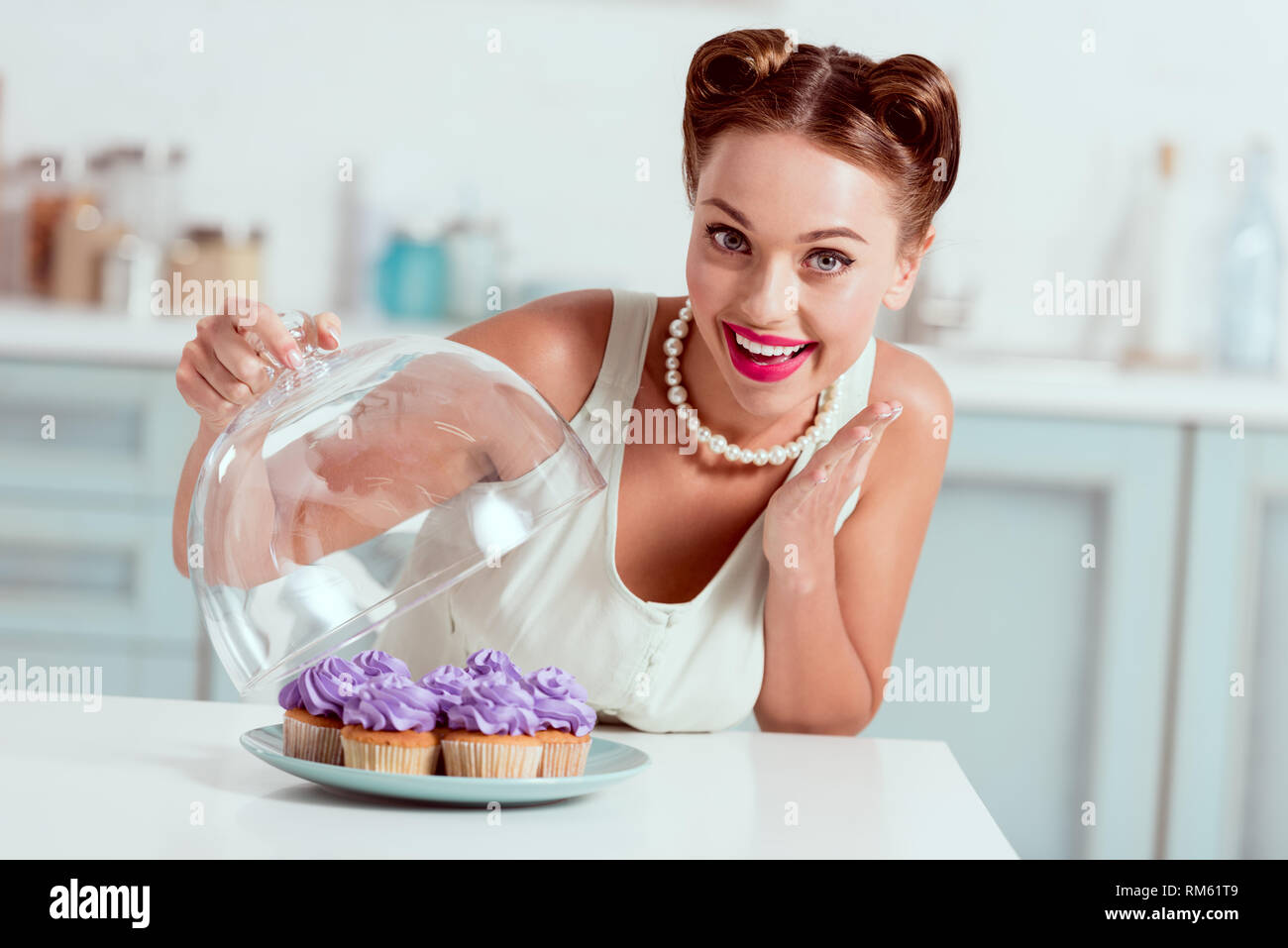 Smiling pin up girl demonstrating plate full of homemade cupcakes Stock ...