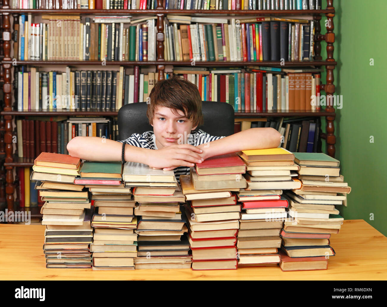 Young teenage boy with big pile of books in library Stock Photo - Alamy