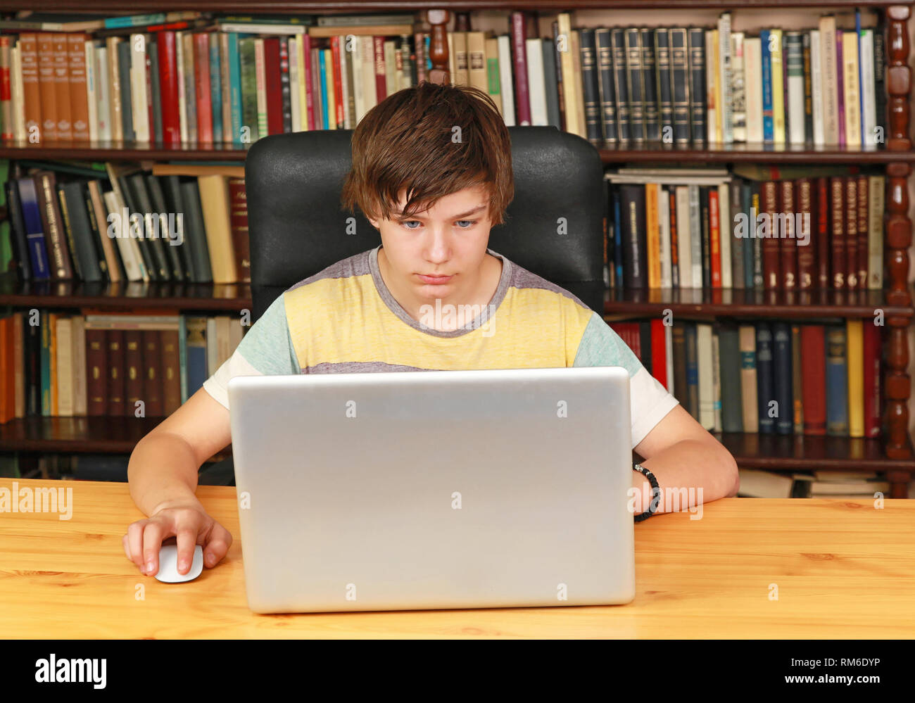 Teenage boy at desk with notebook computer in library Stock Photo - Alamy