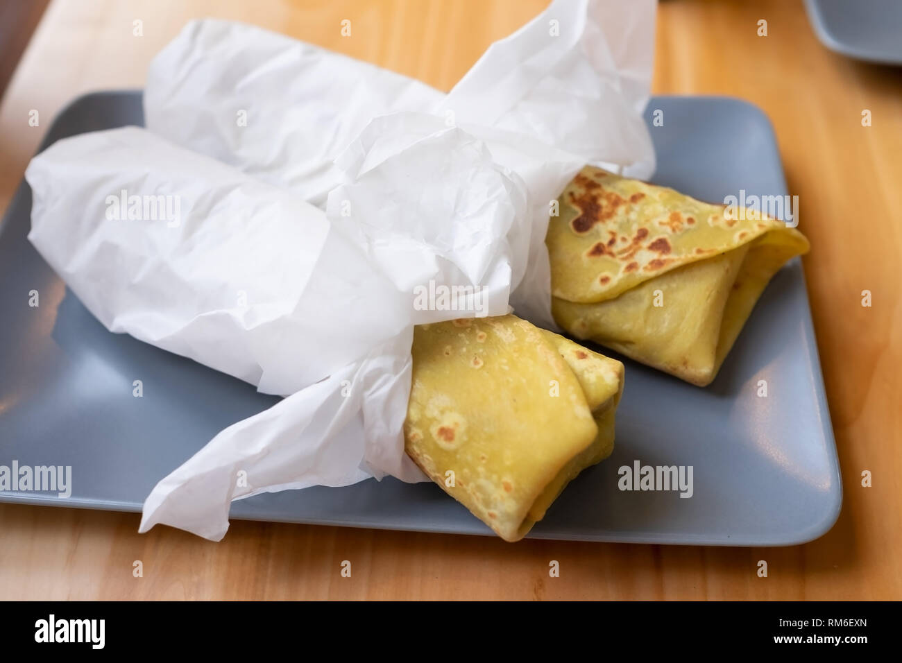 two yellow pancake wtih filling on blue plate Stock Photo - Alamy