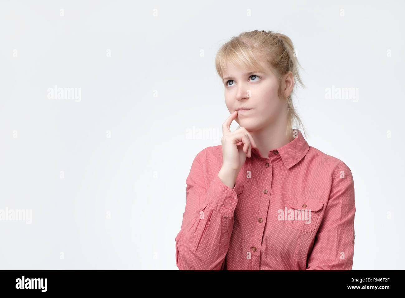 Thinking blonde woman in pink shirt pondering over something Stock ...