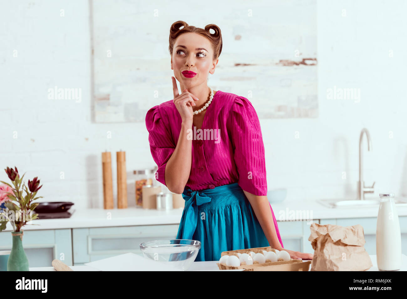 Pretty pin up girl standing by table with different ingredients and ...