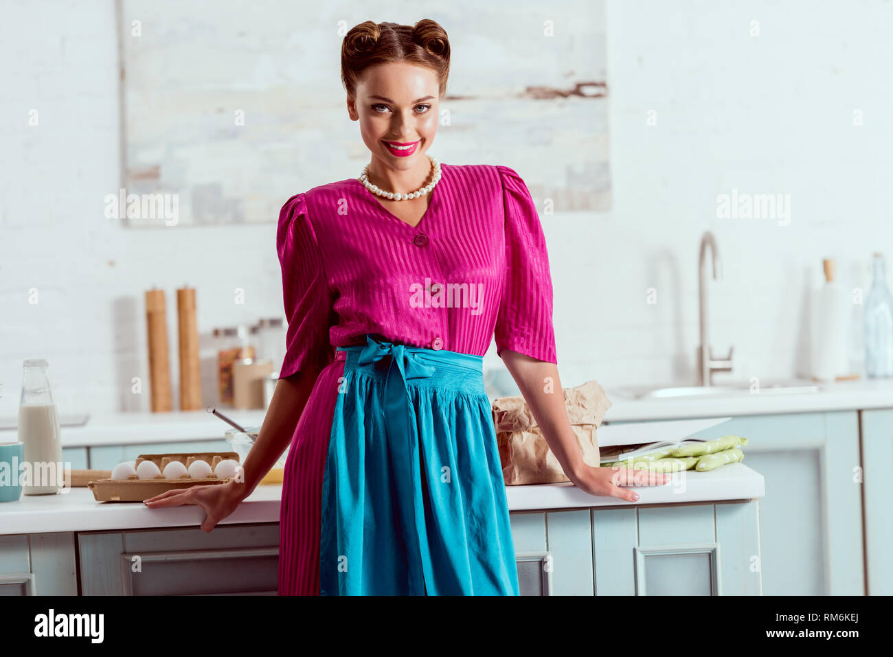 Beautiful pin up girl standing in light blue kitchen near table with ...