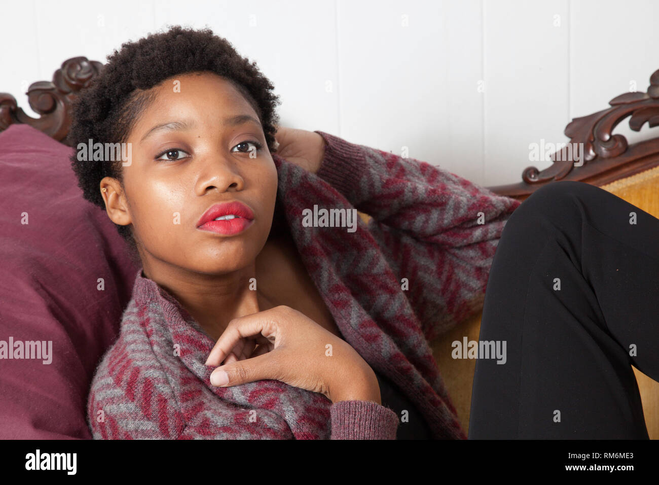 Thoughtful black woman sitting on a couch Stock Photo - Alamy